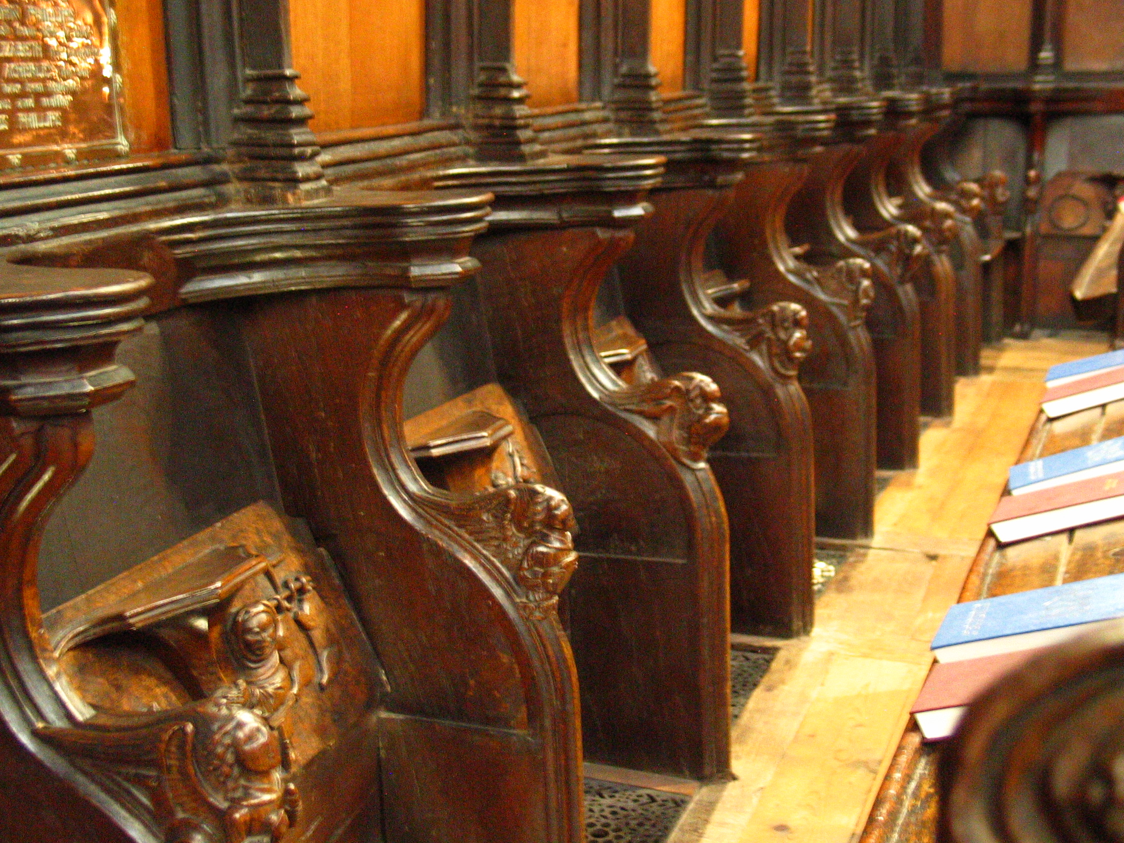 A line of choir stalls, their raised seats revealing the beautifully ...